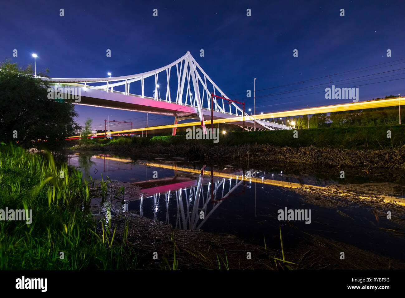 Suspension bridge at night under moonlight with light trails of moving ...