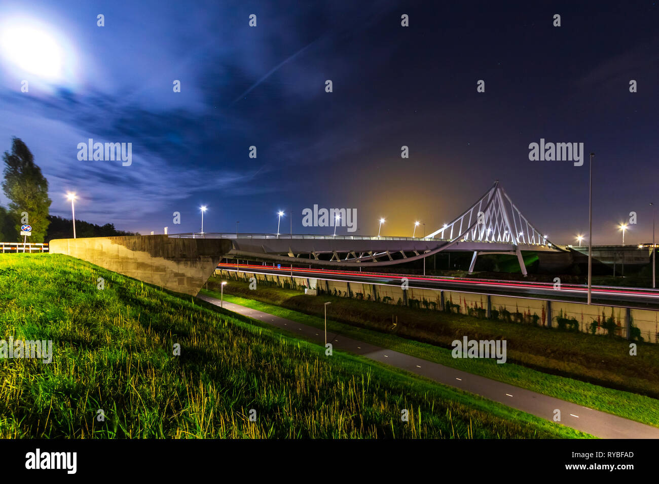 Suspension bridge at night under moonlight with light trails of moving ...