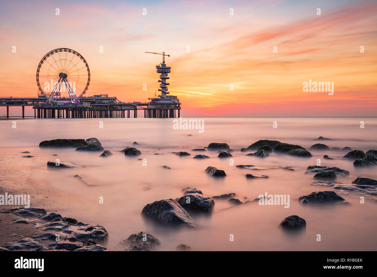 Colorful sunset on coastline, beach, pier and ferris wheel ...