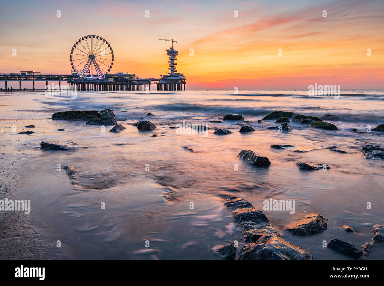 Colorful sunset on coastline, beach, pier and ferries wheel ...