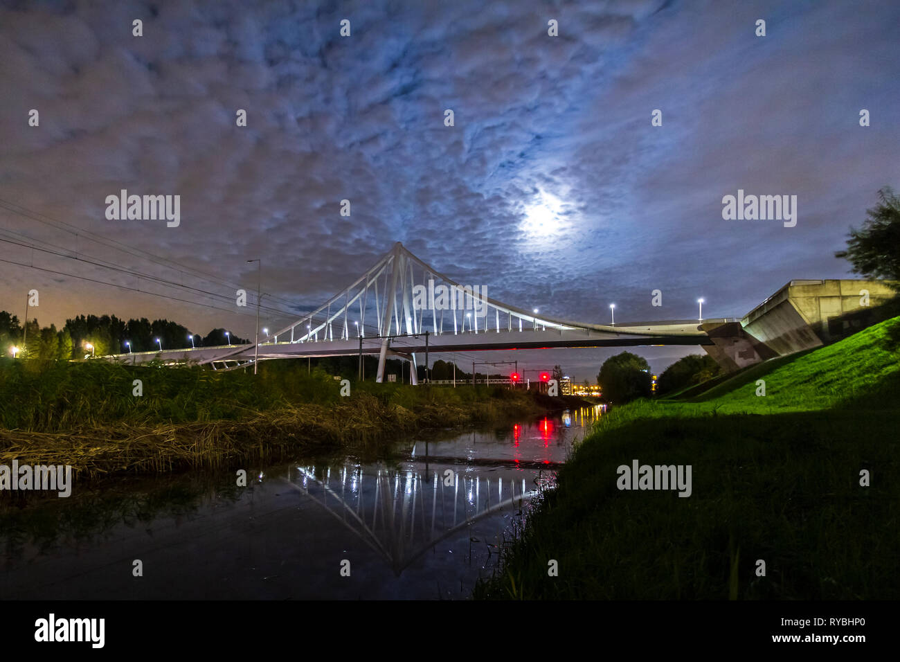 Suspension bridge at night under moonlight with water and reflection ...