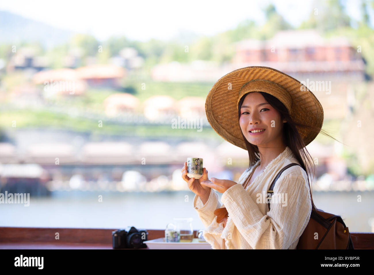 Female tourists are sitting and sipping tea by the reservoir and ...