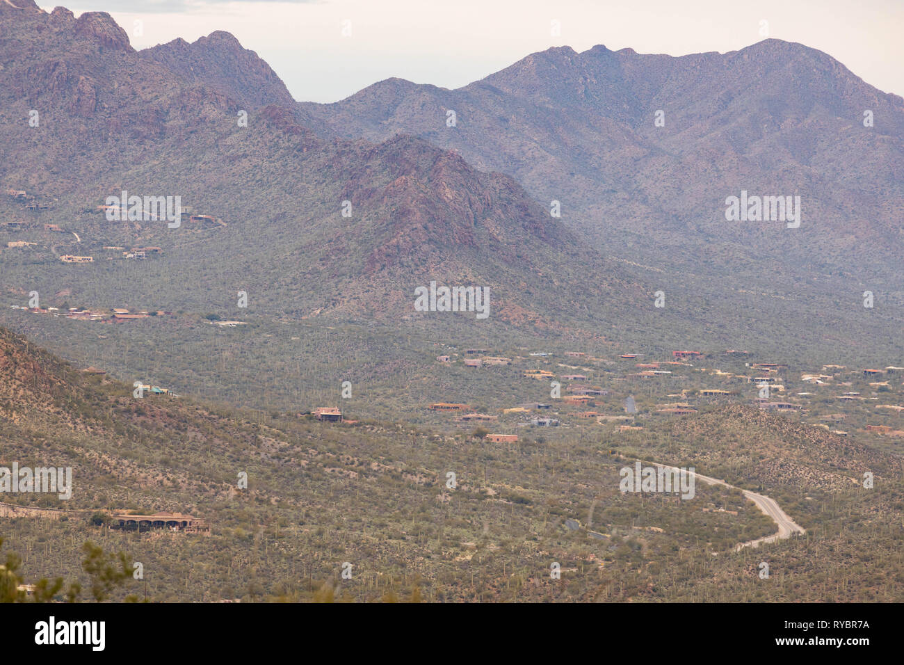 Small country road curves into town at foot of rugged mountains in ...