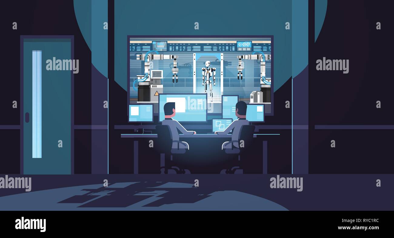 two engineers looking at monitors behind glass robot production modern ...