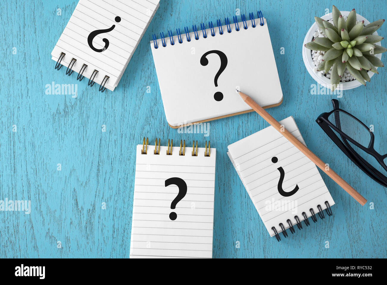 Question marks on notepads on blue wooden background, variety of ...