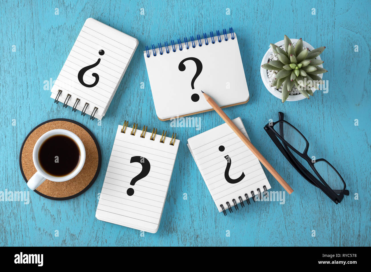 Variety of question marks on notepads with coffee cup on blue wooden ...
