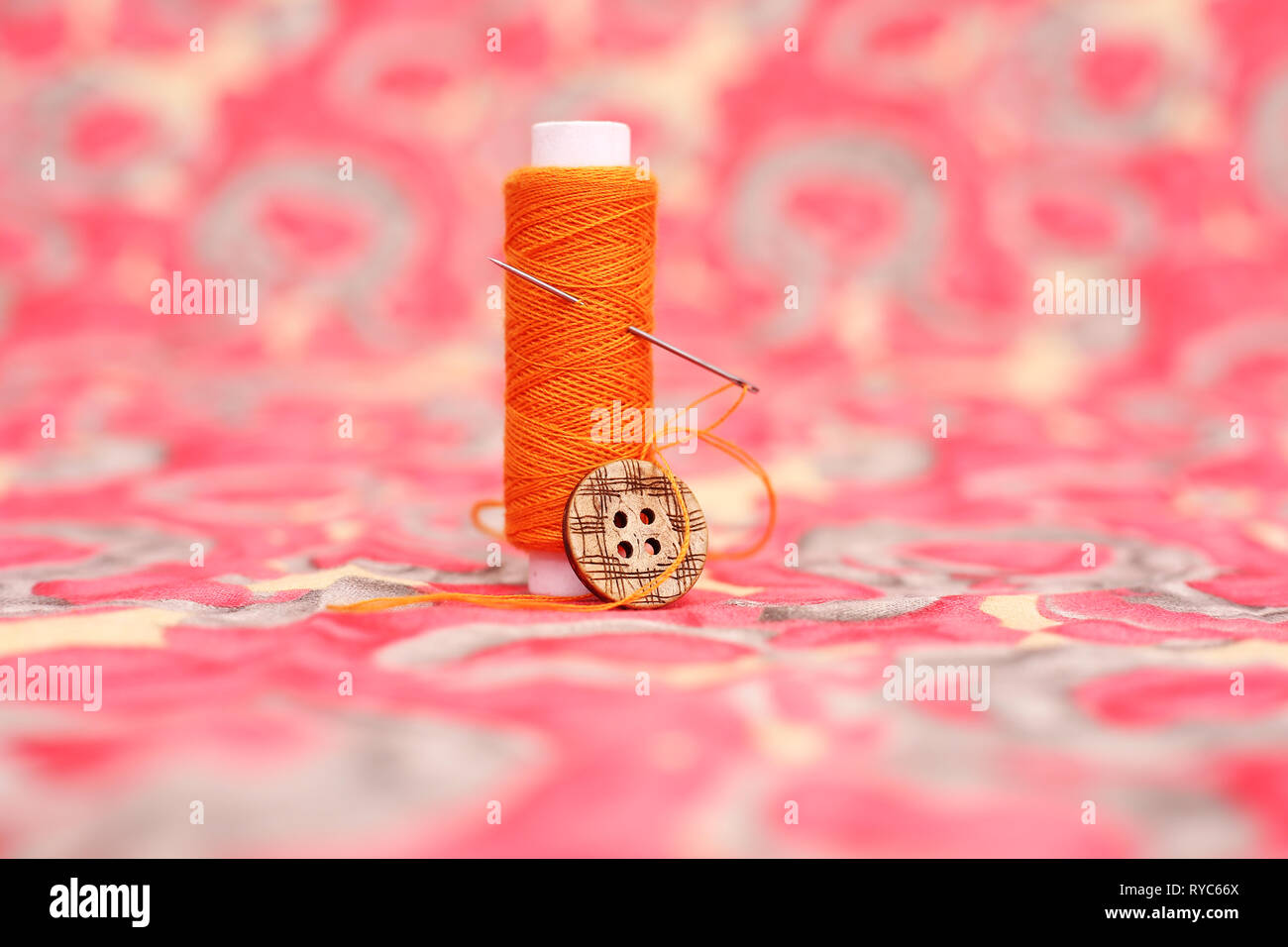 Photo of sewing thread and button. Isolated on the colorful background ...