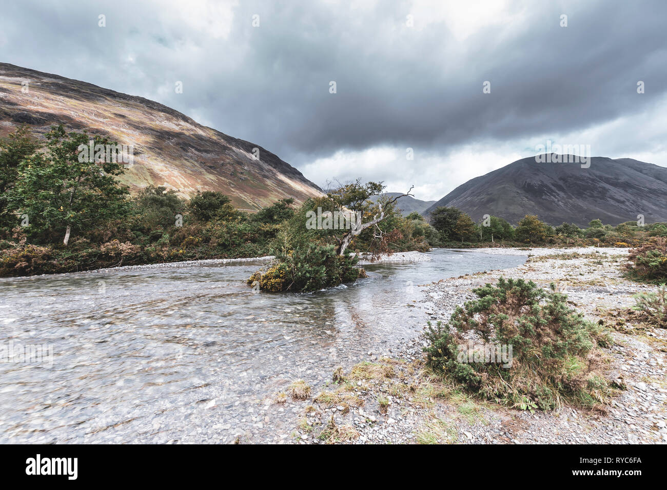 Island with tree on the middle of stream flowing trough scenic valley ...