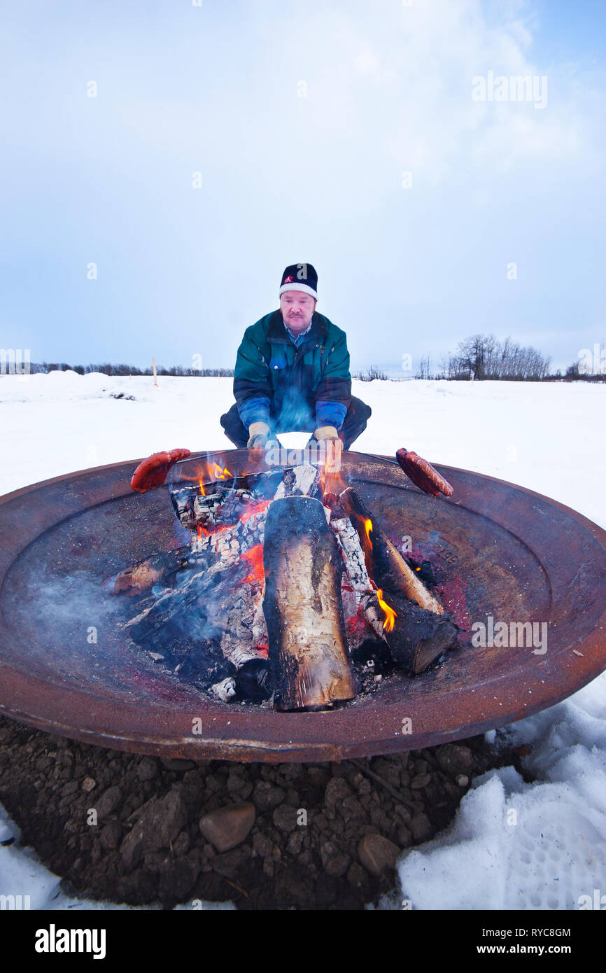 A Canadian man cooking over a fire outdoors in the snow Stock Photo - Alamy
