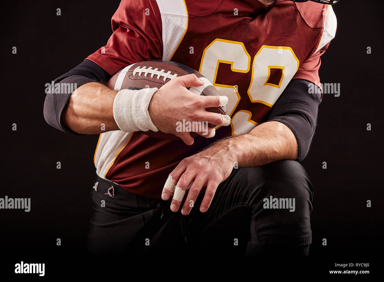 American football player sitting in a position of readiness, hands to ...
