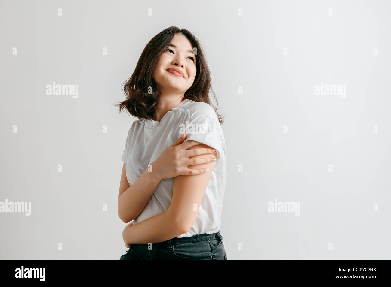 Happy asian woman standing and smiling isolated on gray studio ...
