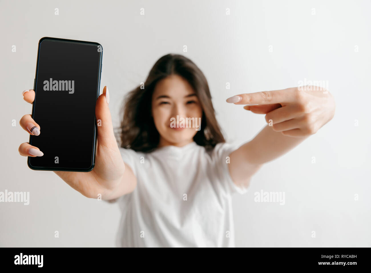 Portrait of a confident casual asian girl showing blank screen of ...