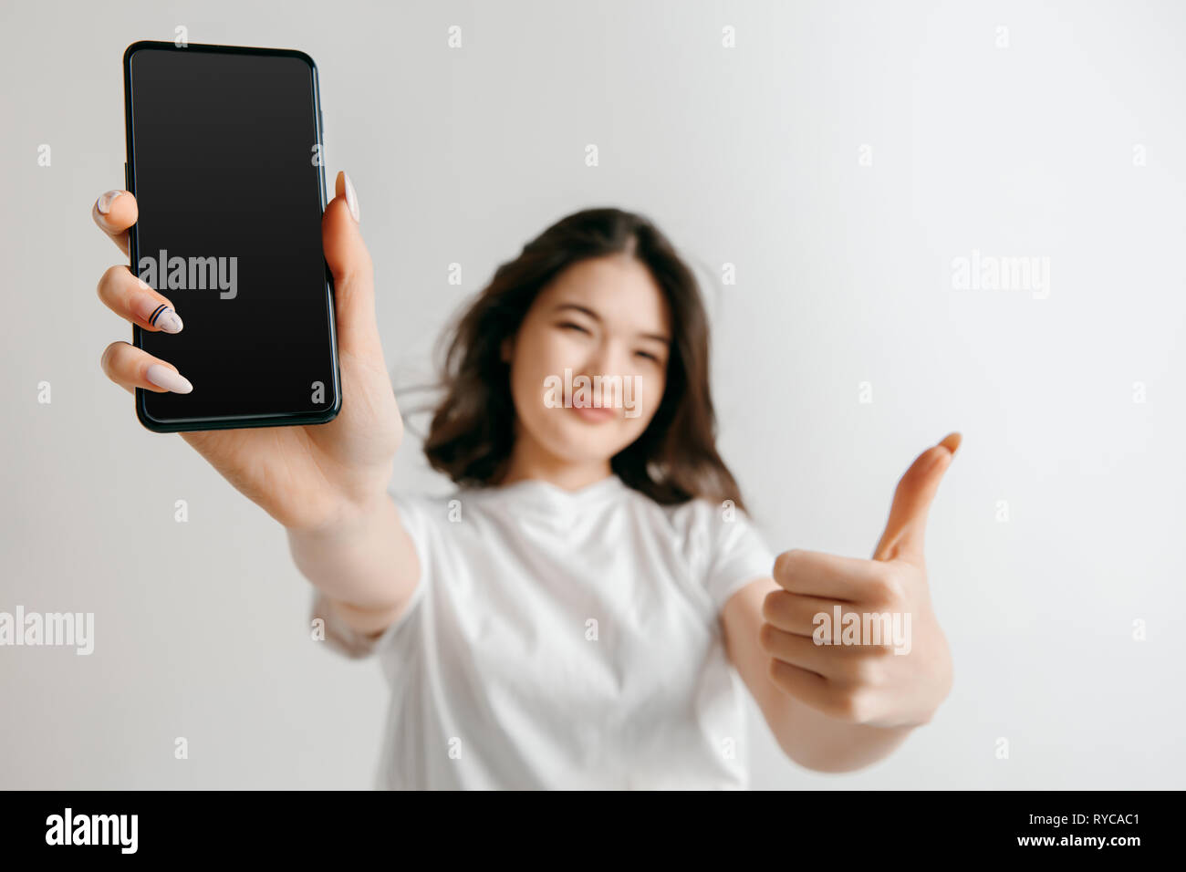 Portrait of a confident casual asian girl showing blank screen of ...