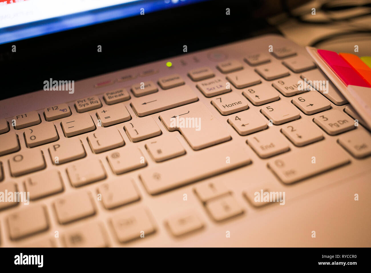 A close up of a white laptop keyboard with focus on "enter" key arrow ...