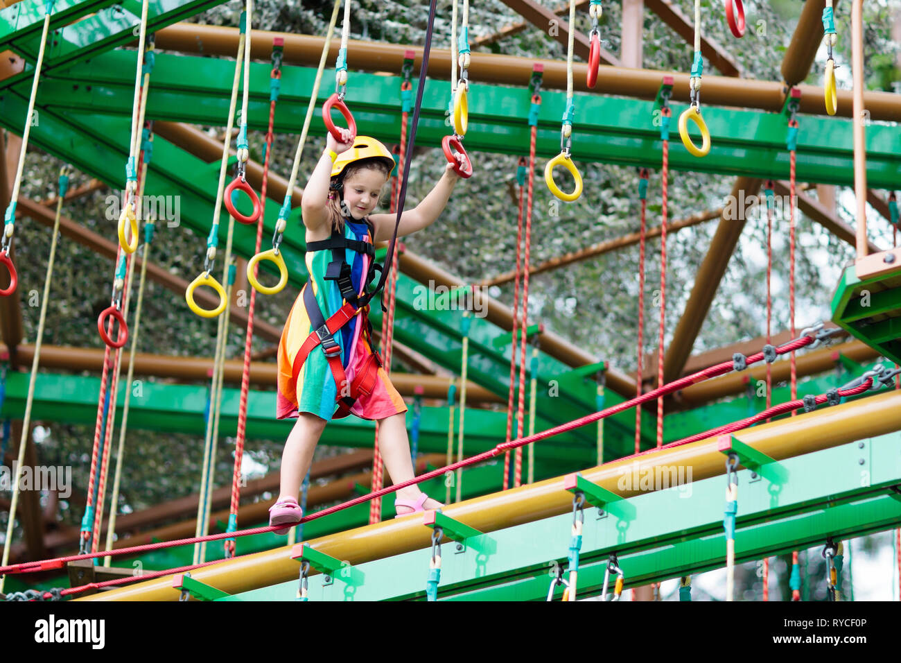Child in forest adventure park. Kids climb on high rope trail. Agility ...