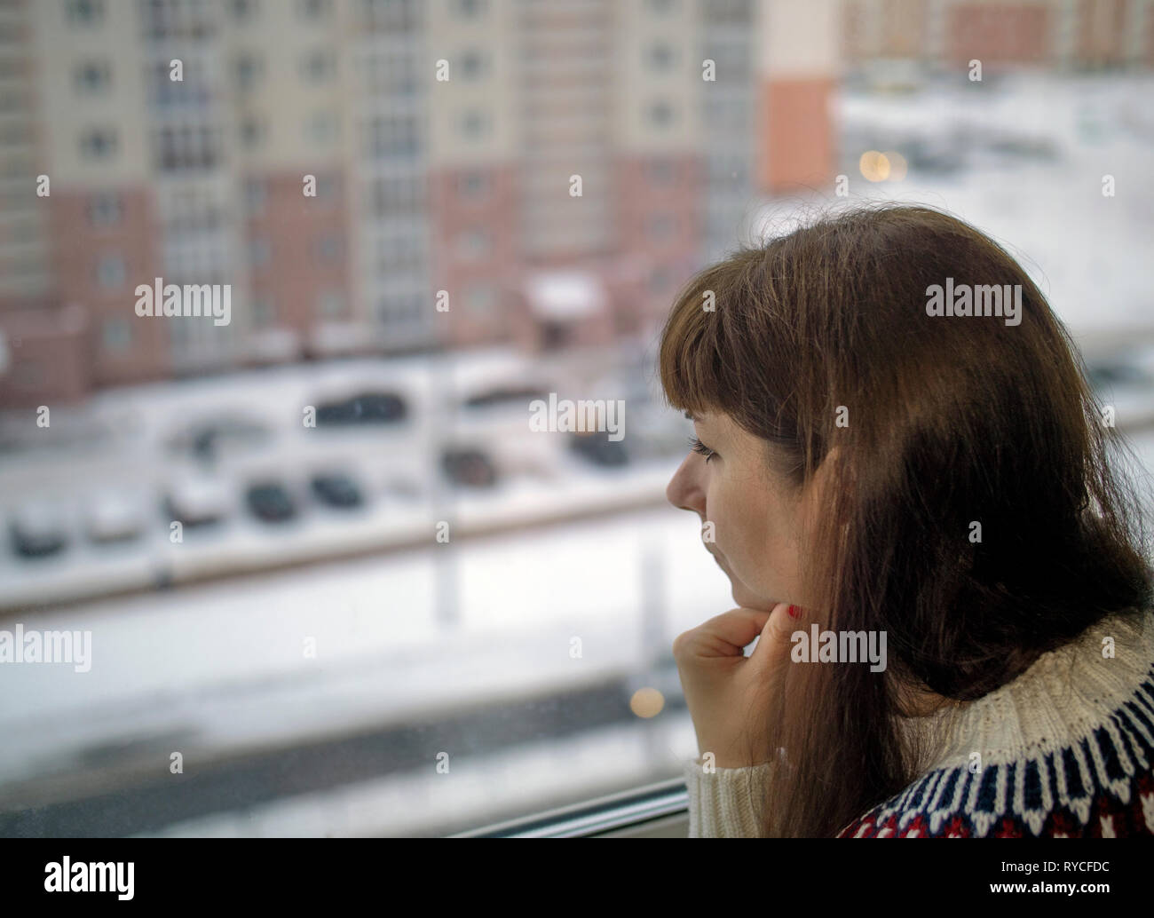 Young pretty woman looking sad out the window to the street outside ...