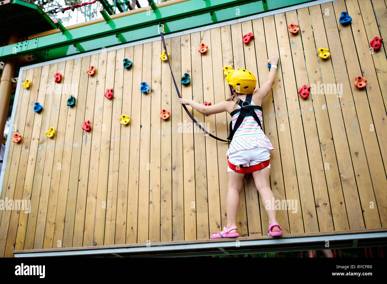 Child in forest adventure park. Kids climb on high rope trail. Agility ...