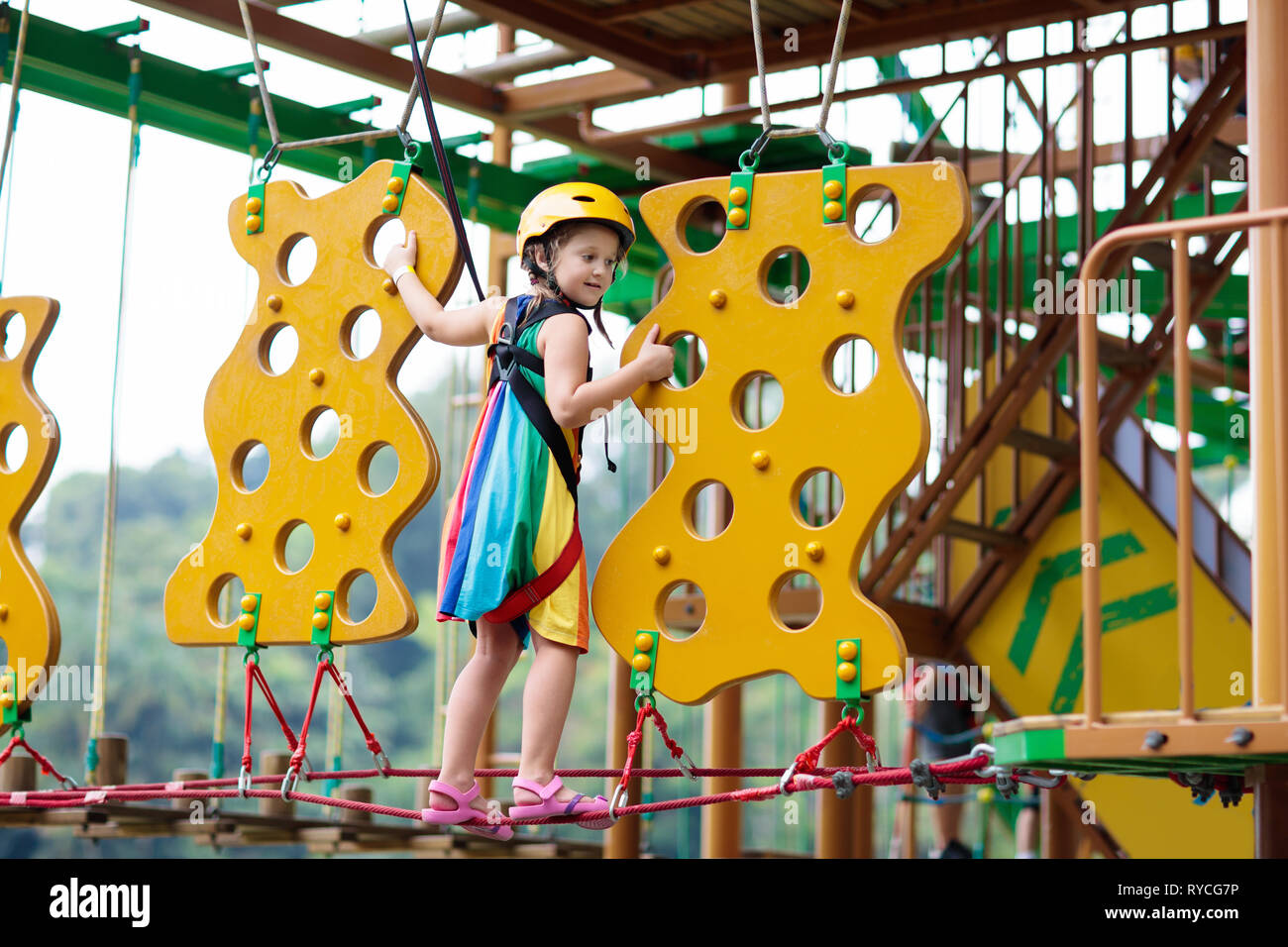 Child in forest adventure park. Kids climb on high rope trail. Agility ...