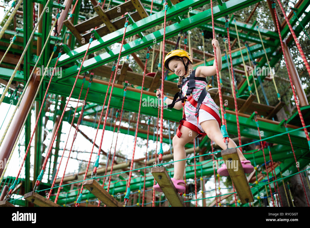 Child in forest adventure park. Kids climb on high rope trail. Agility ...