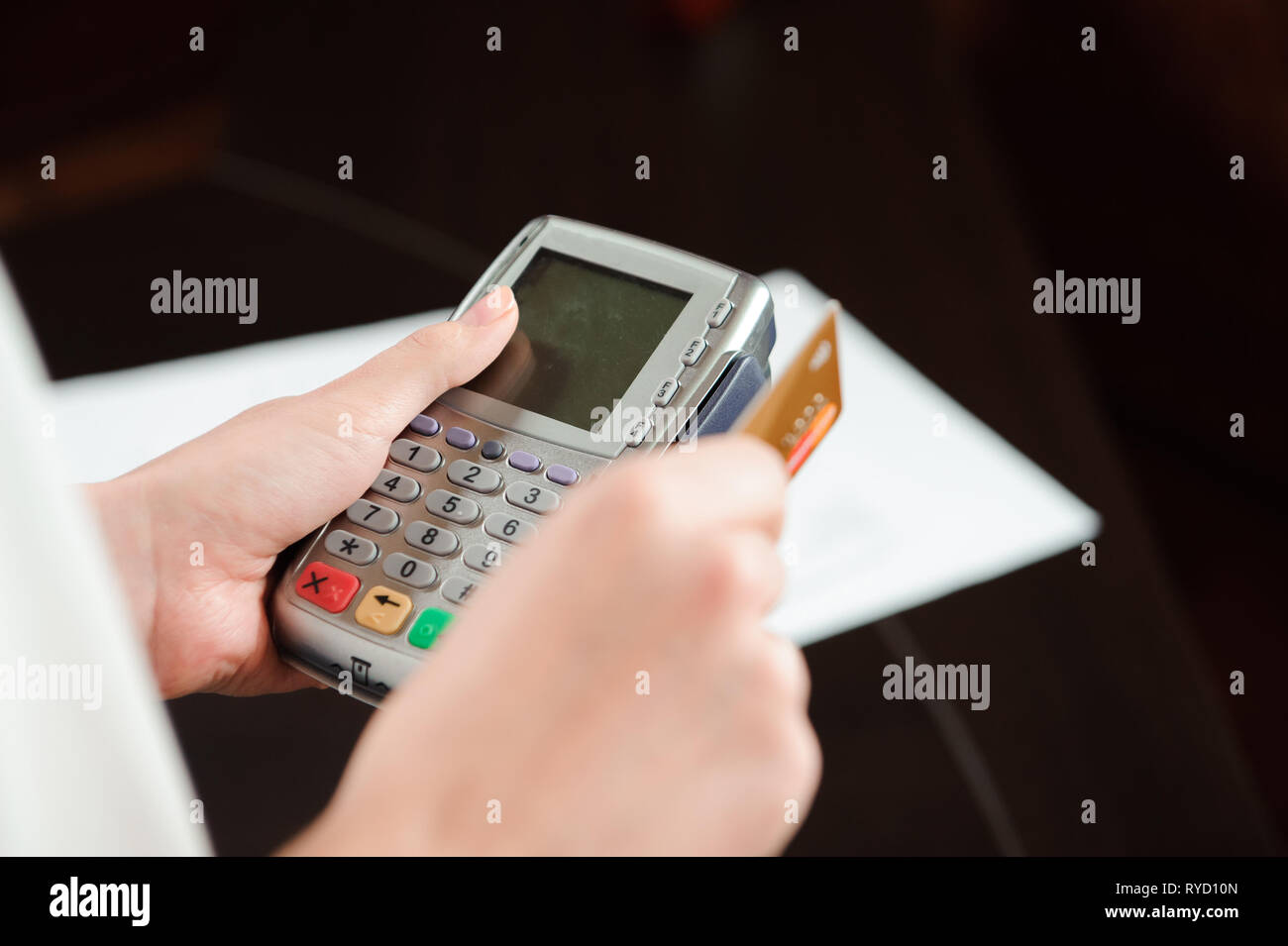Hand swiping debit card on pos terminal. Business people in office ...