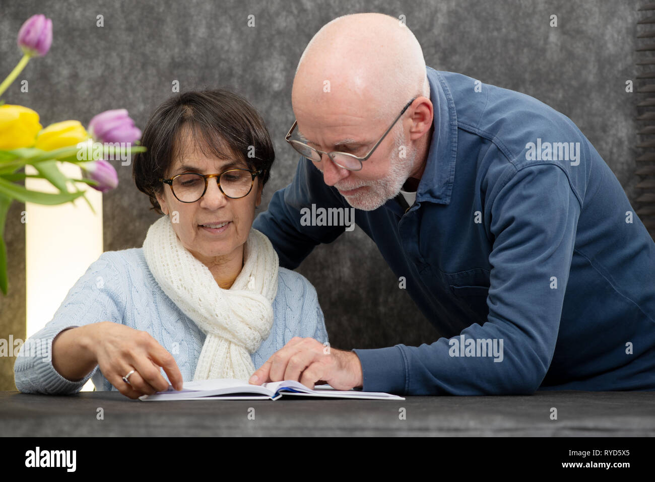 a couple of senior reading a book at home Stock Photo - Alamy