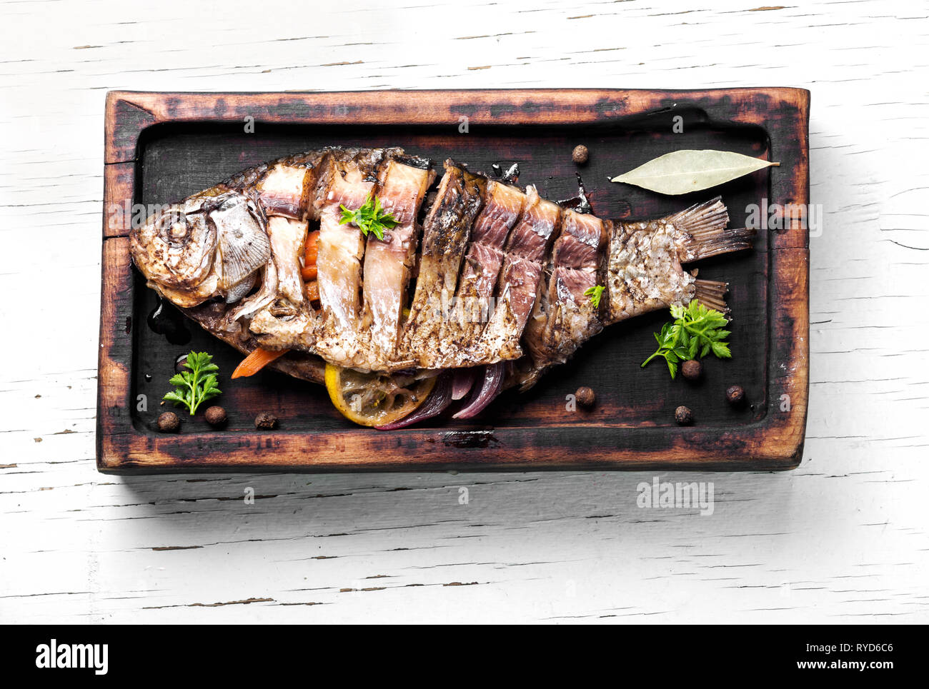 Grilled whole fish loaded with citrus and spices on rustic wooden table ...