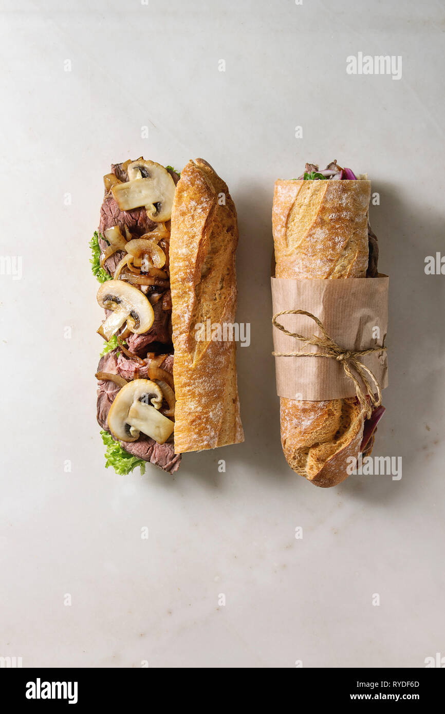 Opened and tied beef baguette sandwich with champignon mushrooms, green ...