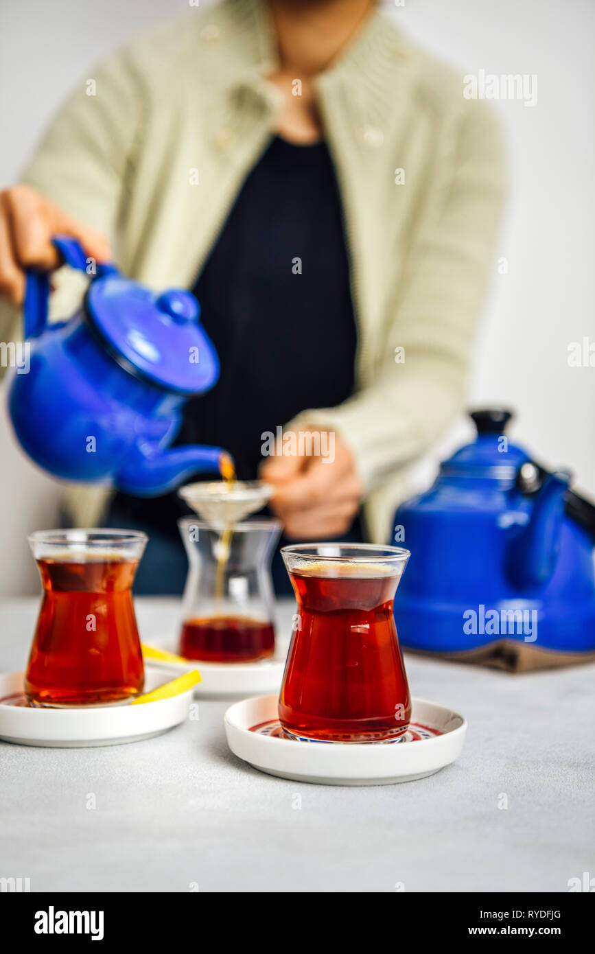 Woman pouring Turkish tea into a tea glass from a nostalgic teapot ...