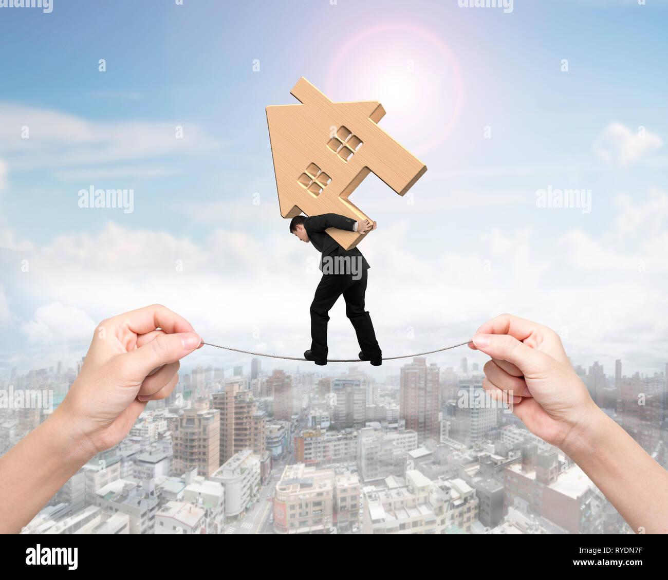 Man carrying wooden house and balancing on tightrope with two hands ...