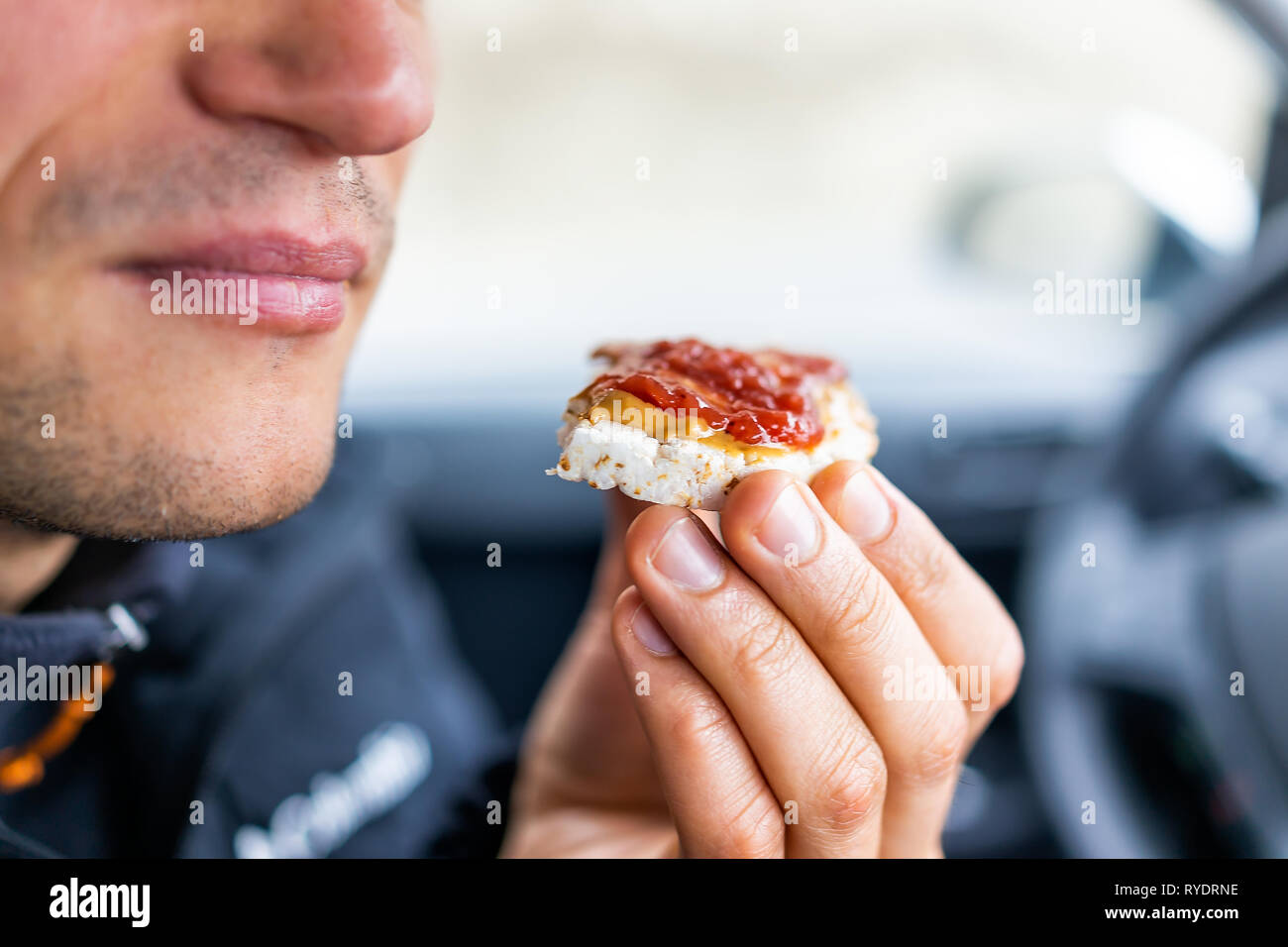 Macro closeup of man hand holding one rice cake by mouth in car road ...