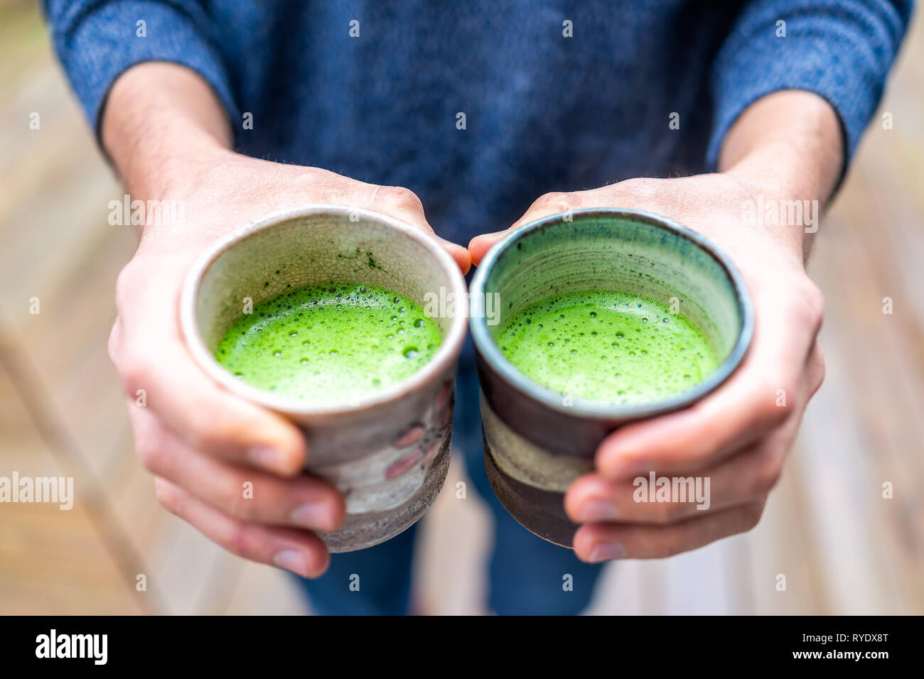 Closeup of man person hands holding two tea cups outside on backyard ...