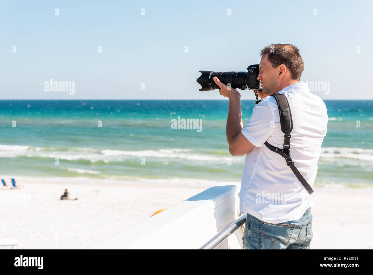 Young photographer man taking picture on beach during sunny day in ...