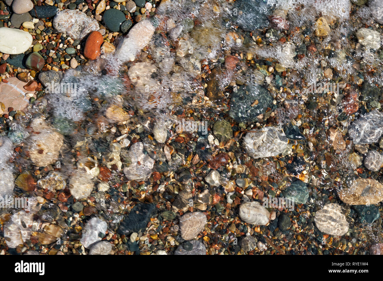 Wet pebble stones in water on Petra tou Romiou or Aphrodite Rock Beach ...