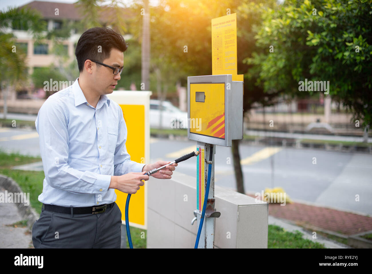 asian man pumping air to his car tyre Stock Photo - Alamy