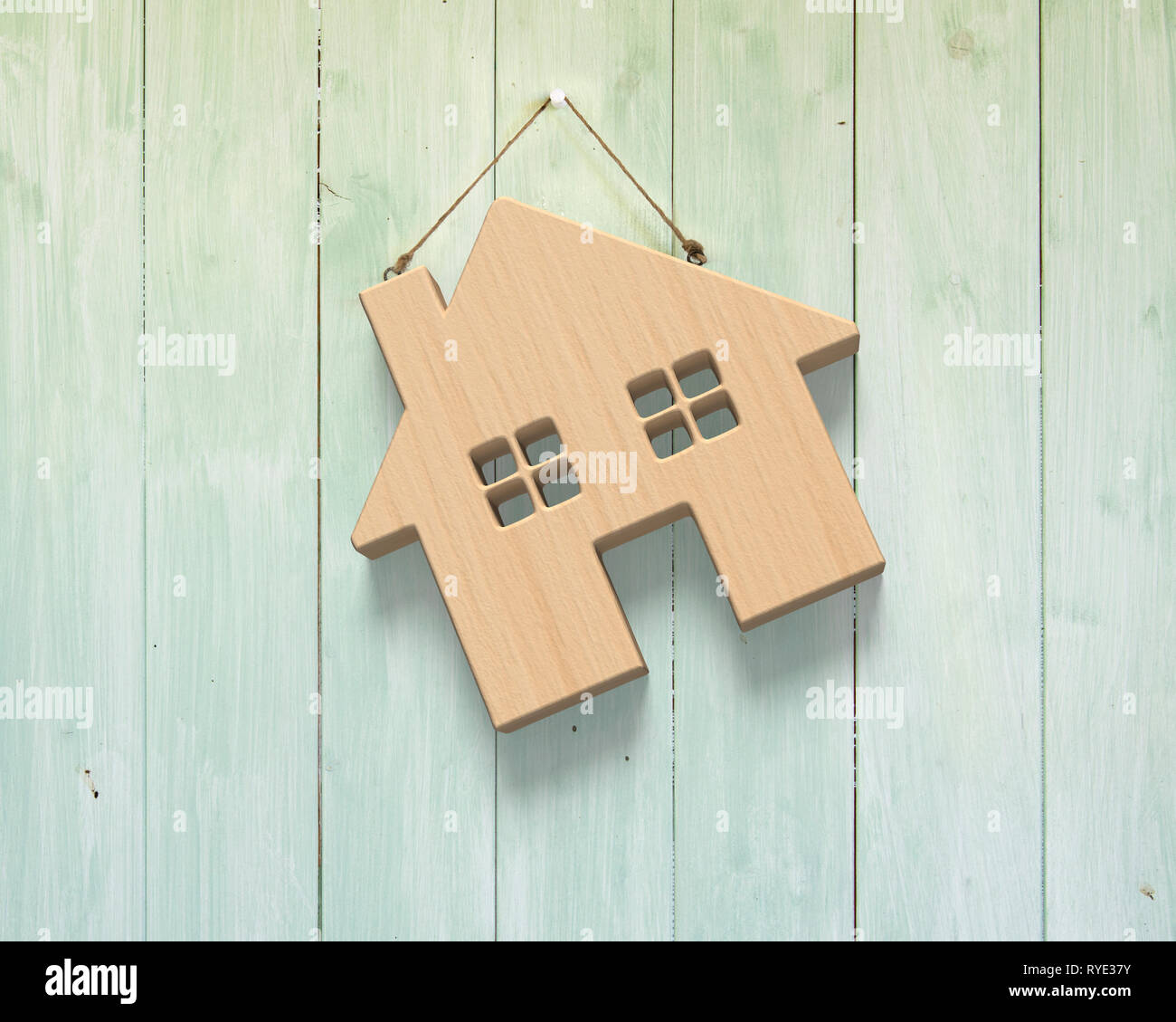 Wooden house hanging on green wood wall background Stock Photo - Alamy