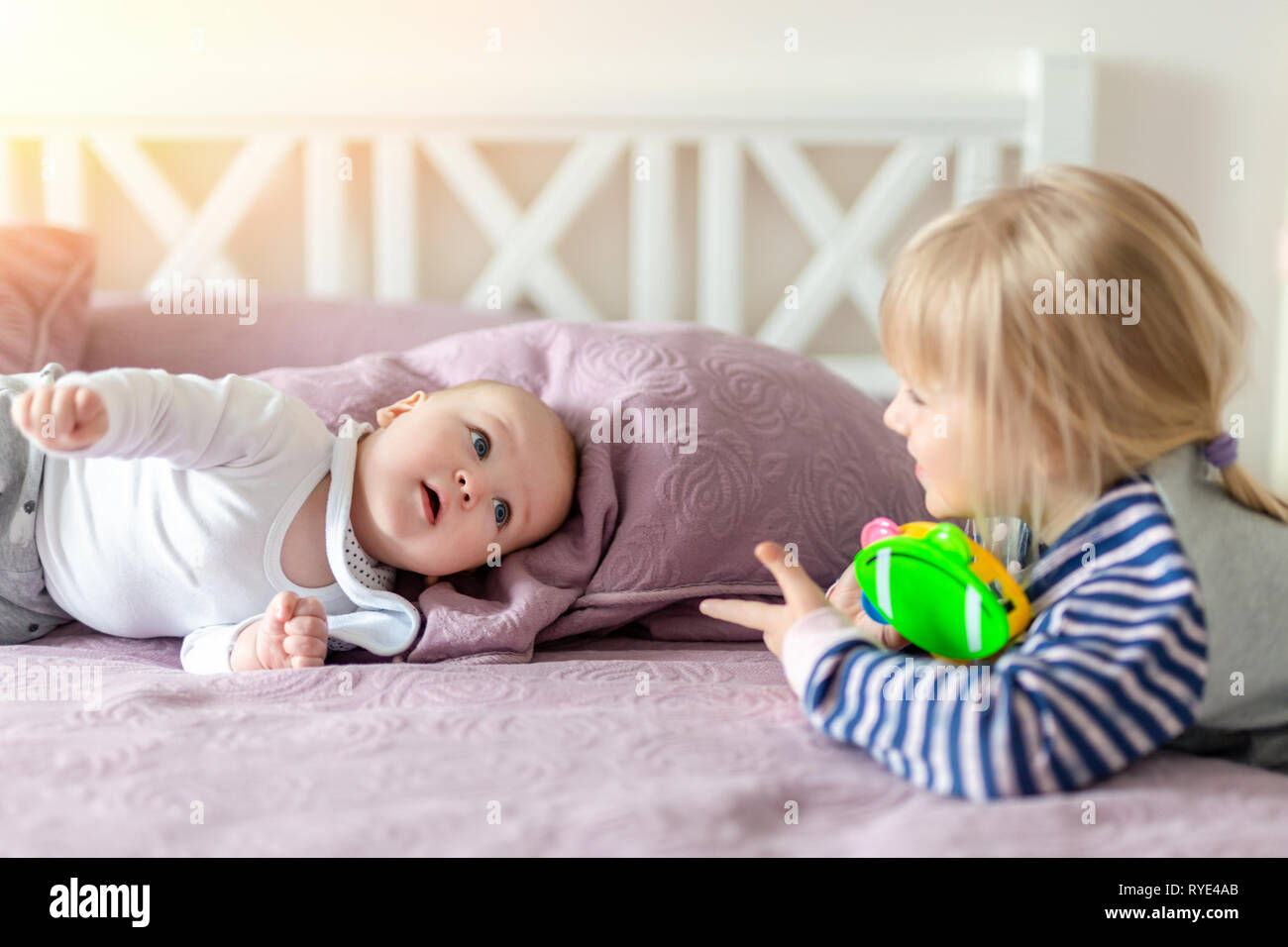 Two cute little siblings playing together on bed. Sister and brother ...