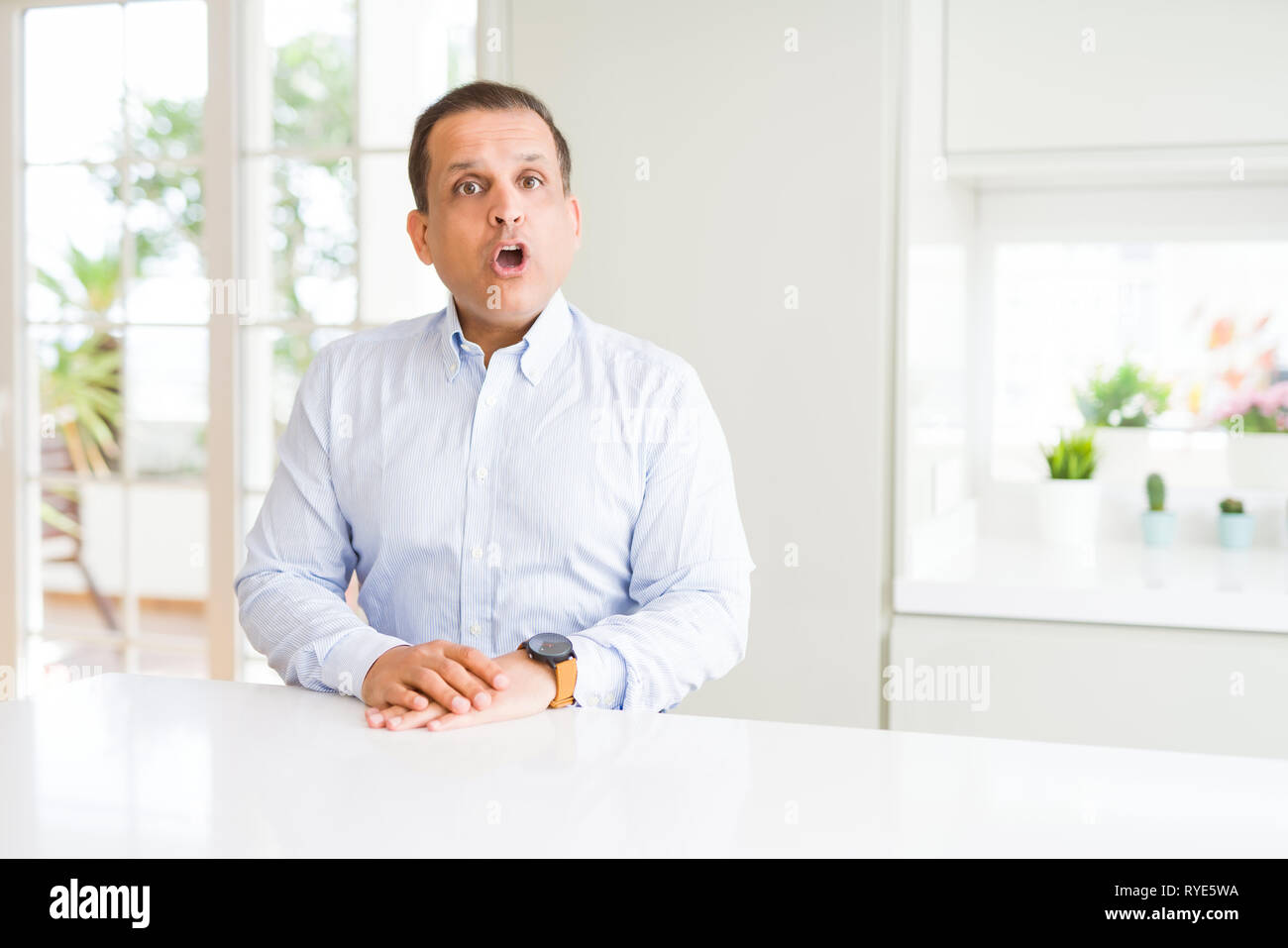 Middle age man sitting at home afraid and shocked with surprise ...