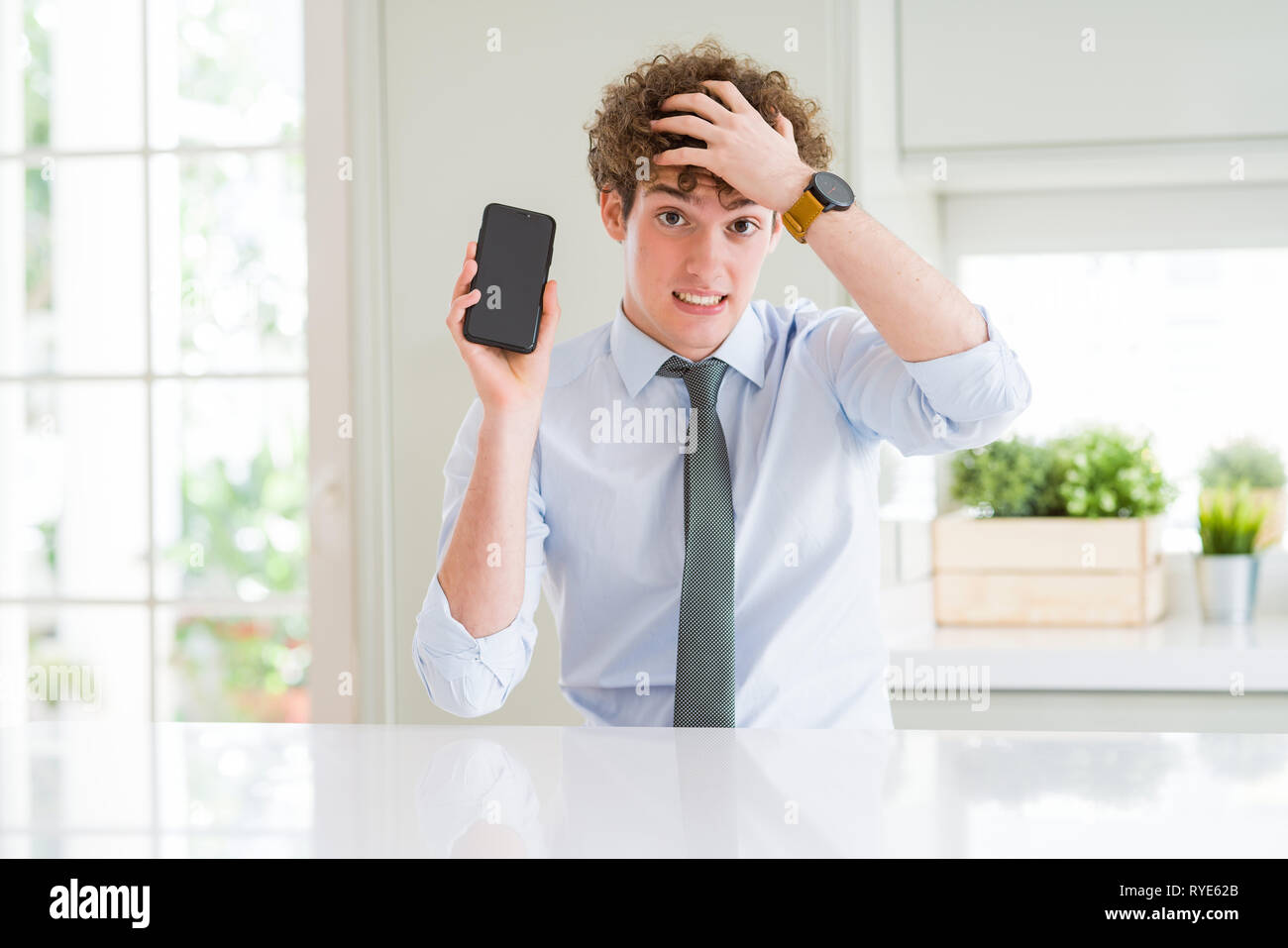 Young business man showing smartphone screen at the office stressed ...