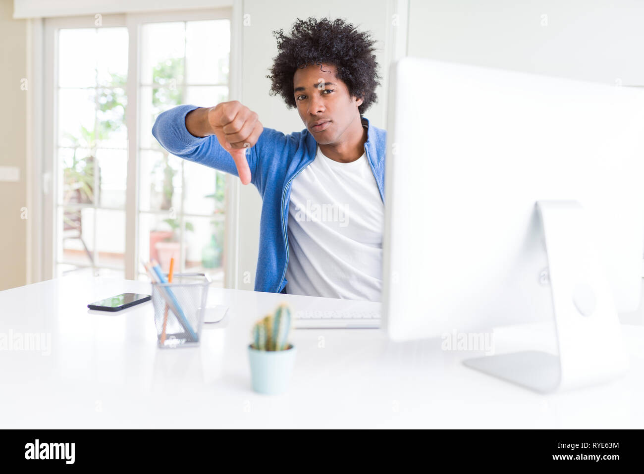 African American man working using computer with angry face, negative ...