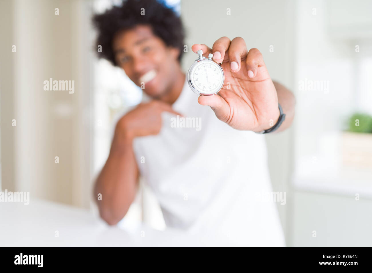 African American man holding stopwatch with surprise face pointing ...