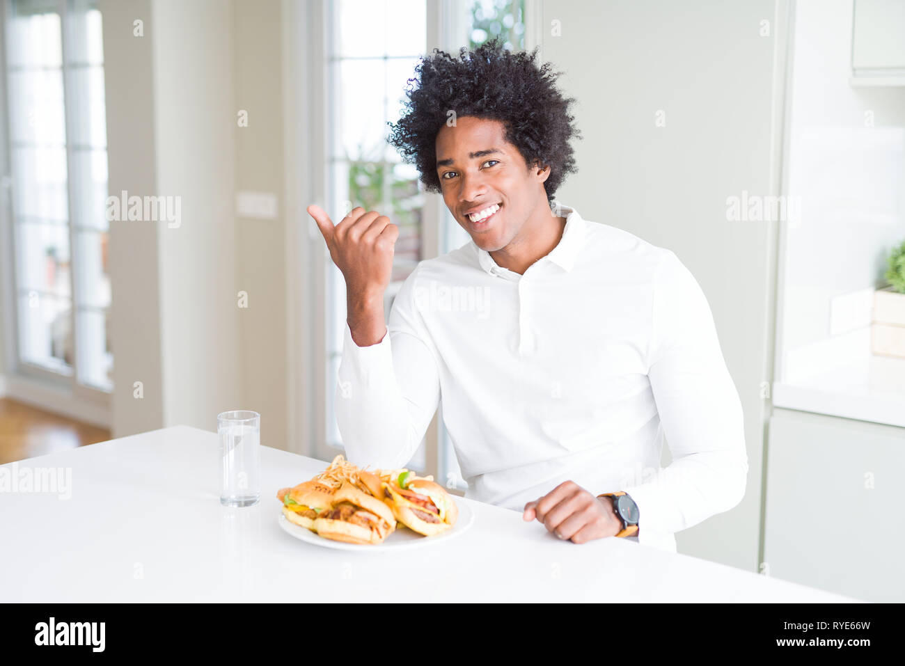 African American hungry man eating hamburger for lunch smiling with ...