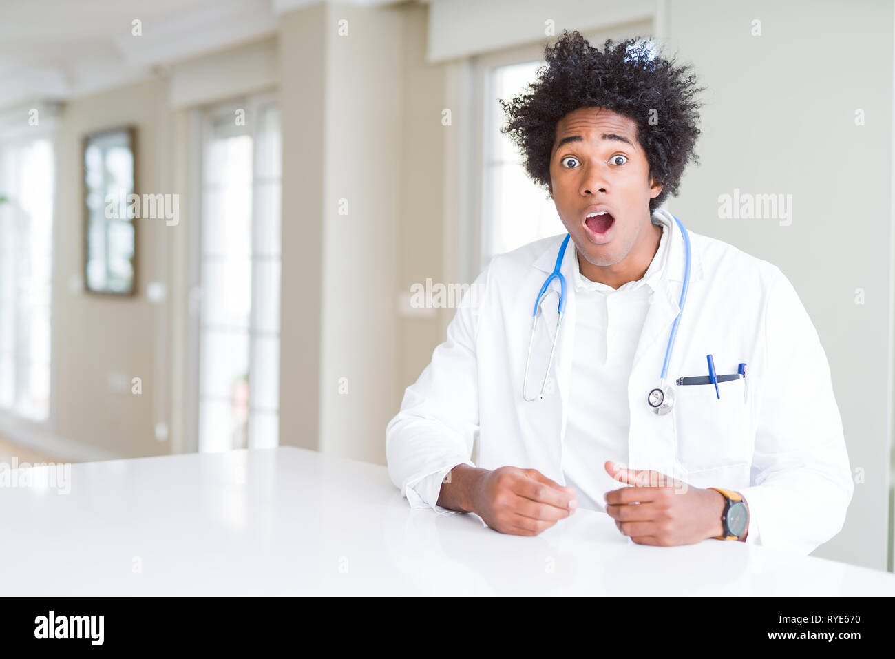 African American doctor man at the clinic afraid and shocked with ...