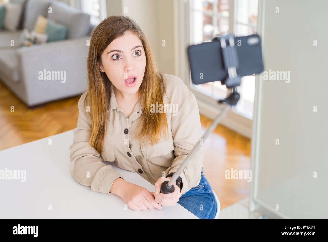 Beautiful young woman taking a picture using selfie stick scared in ...