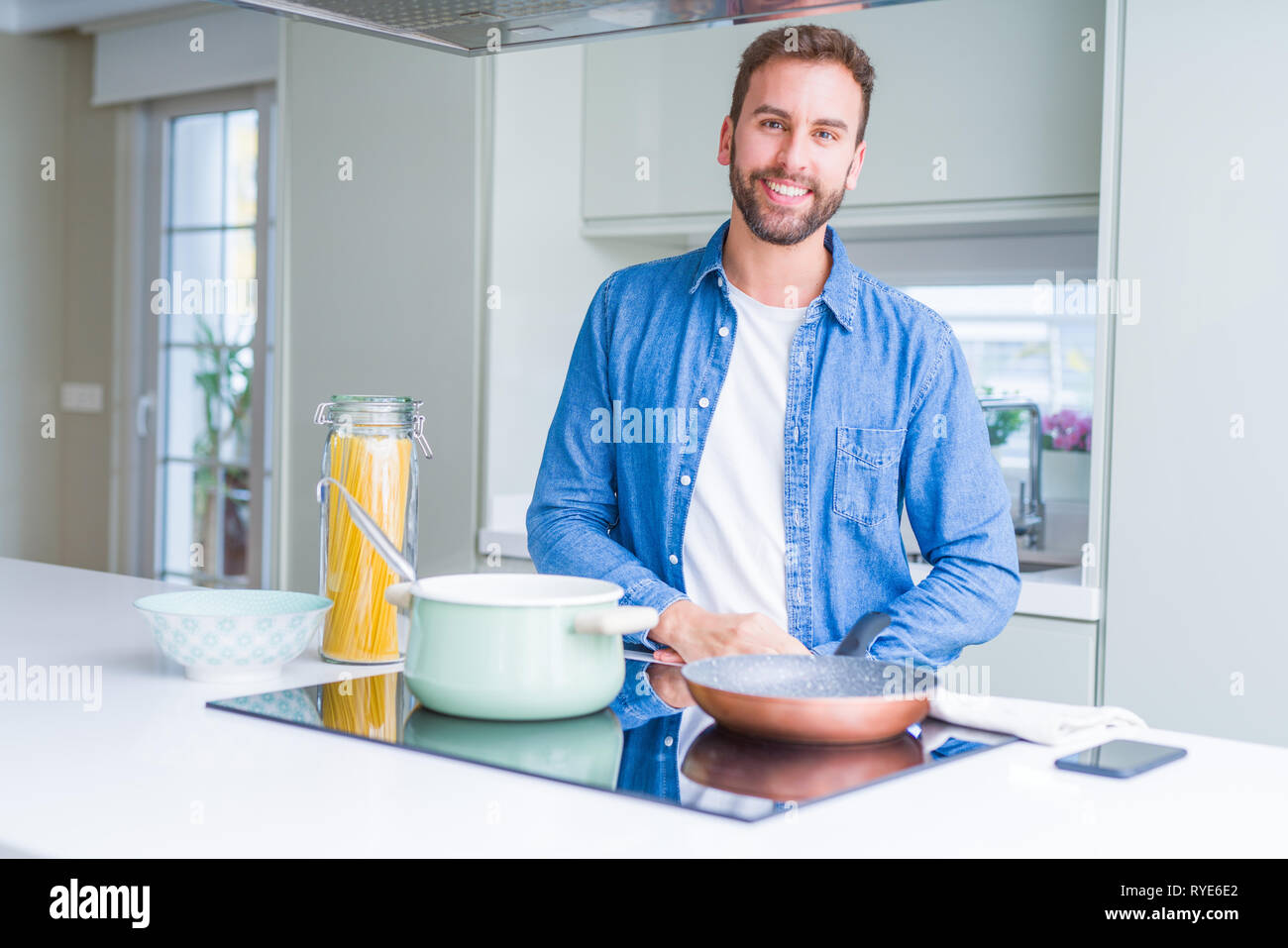 Handsome man cooking italian spaghetti pasta at the kitchen with a ...