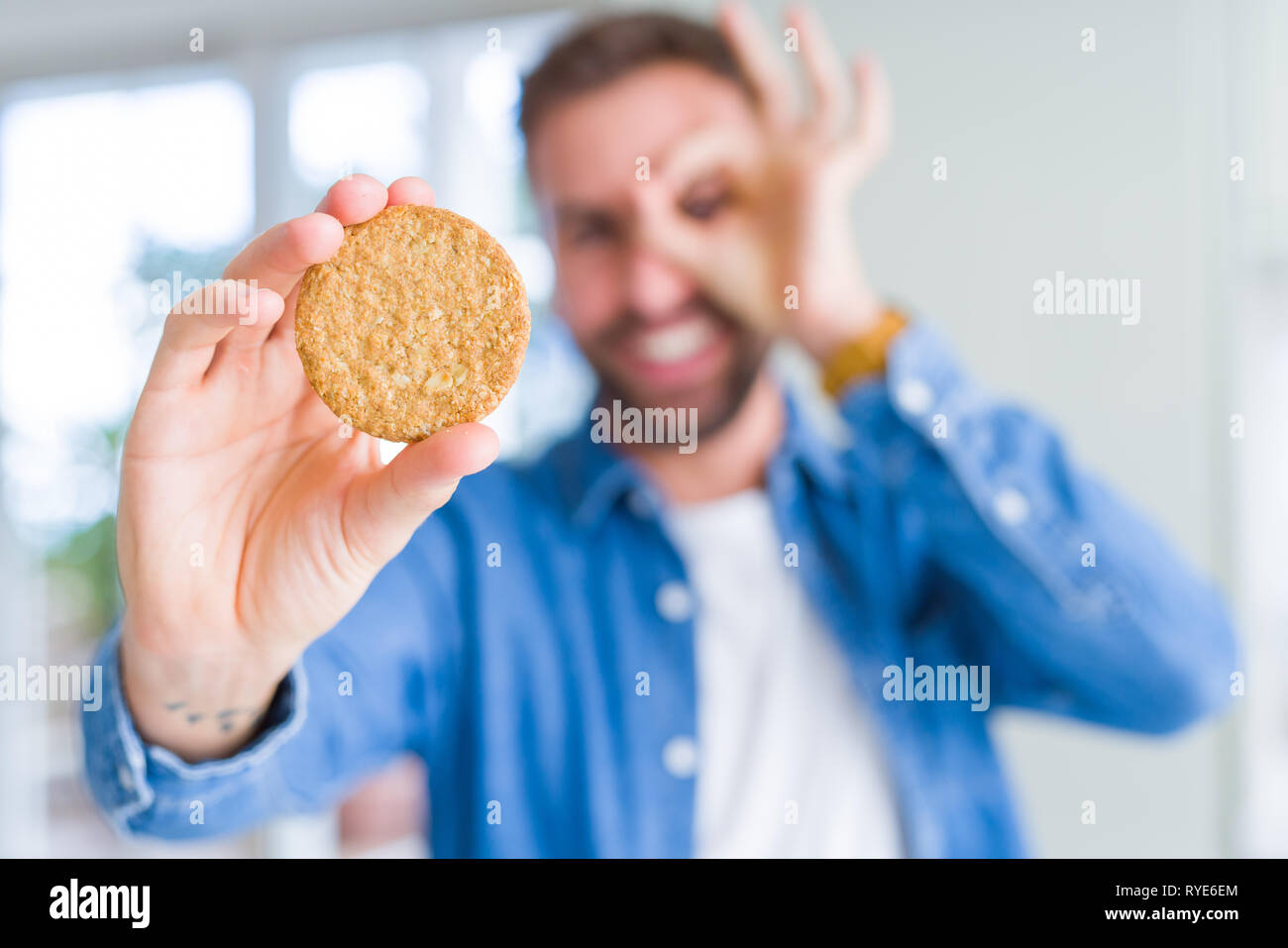 Handsome man eating healthy whole grain biscuit with happy face smiling ...