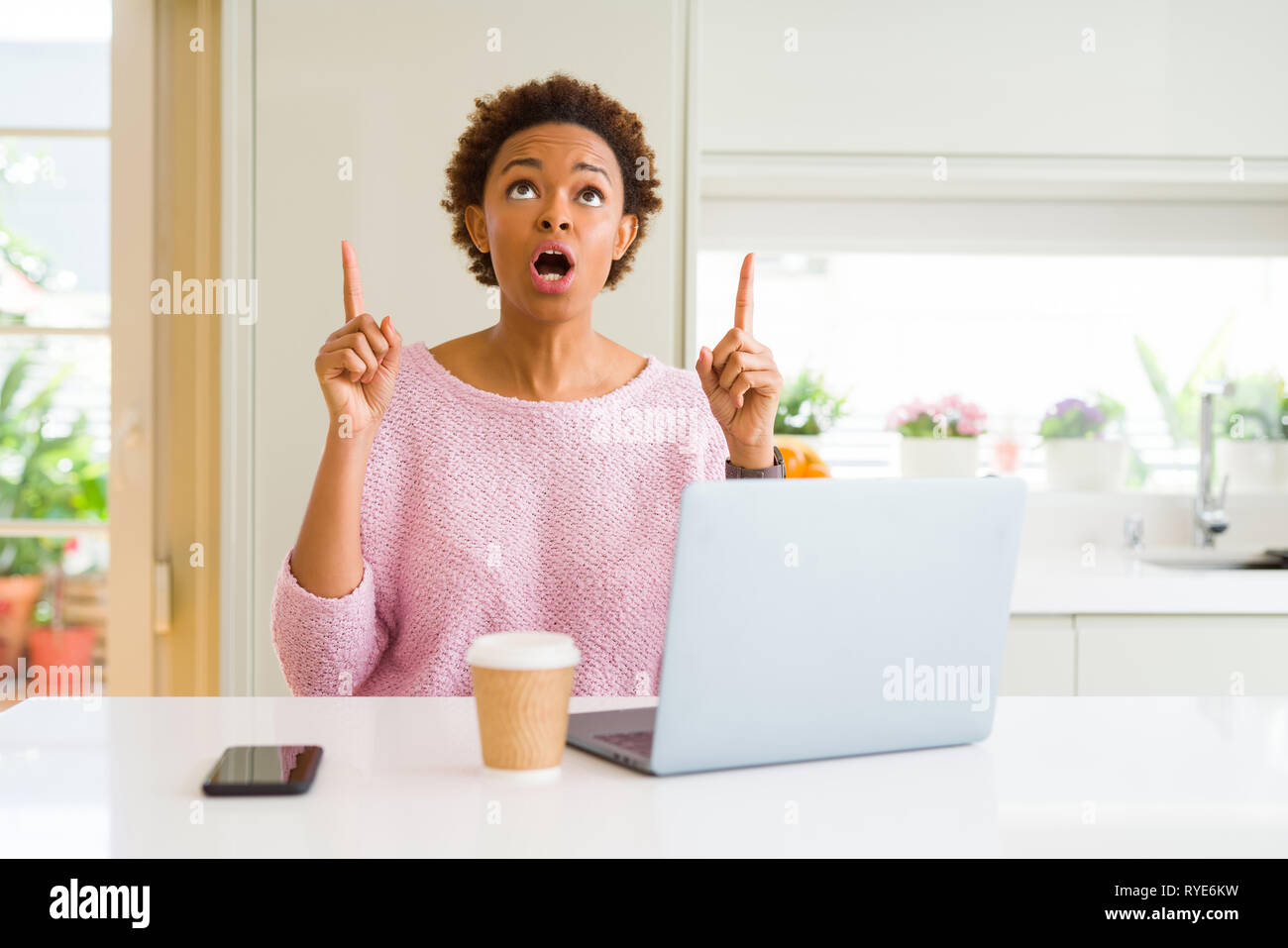 Young african american woman working using computer laptop amazed and ...