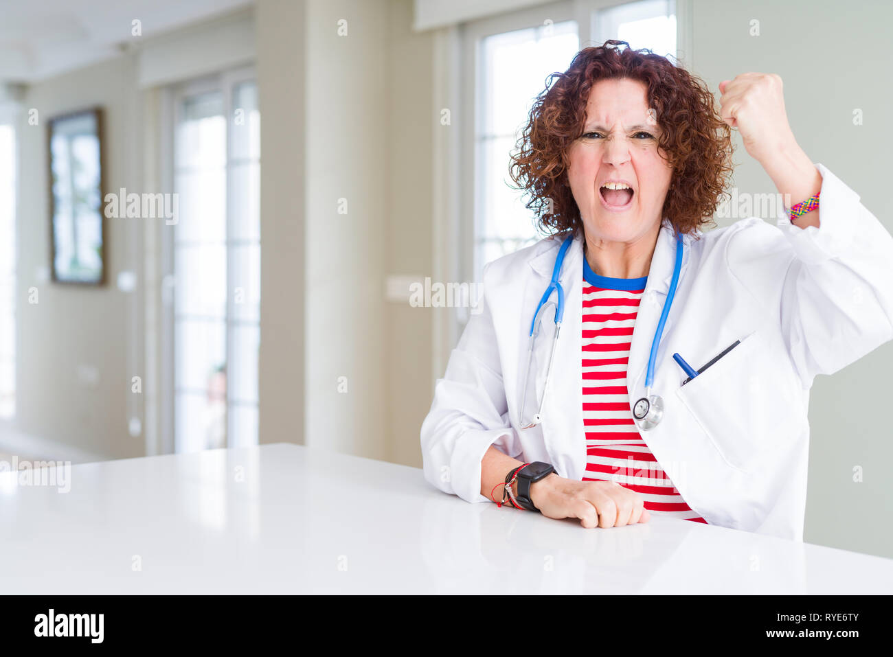 Senior doctor woman wearing medical robe at the clinic angry and mad ...
