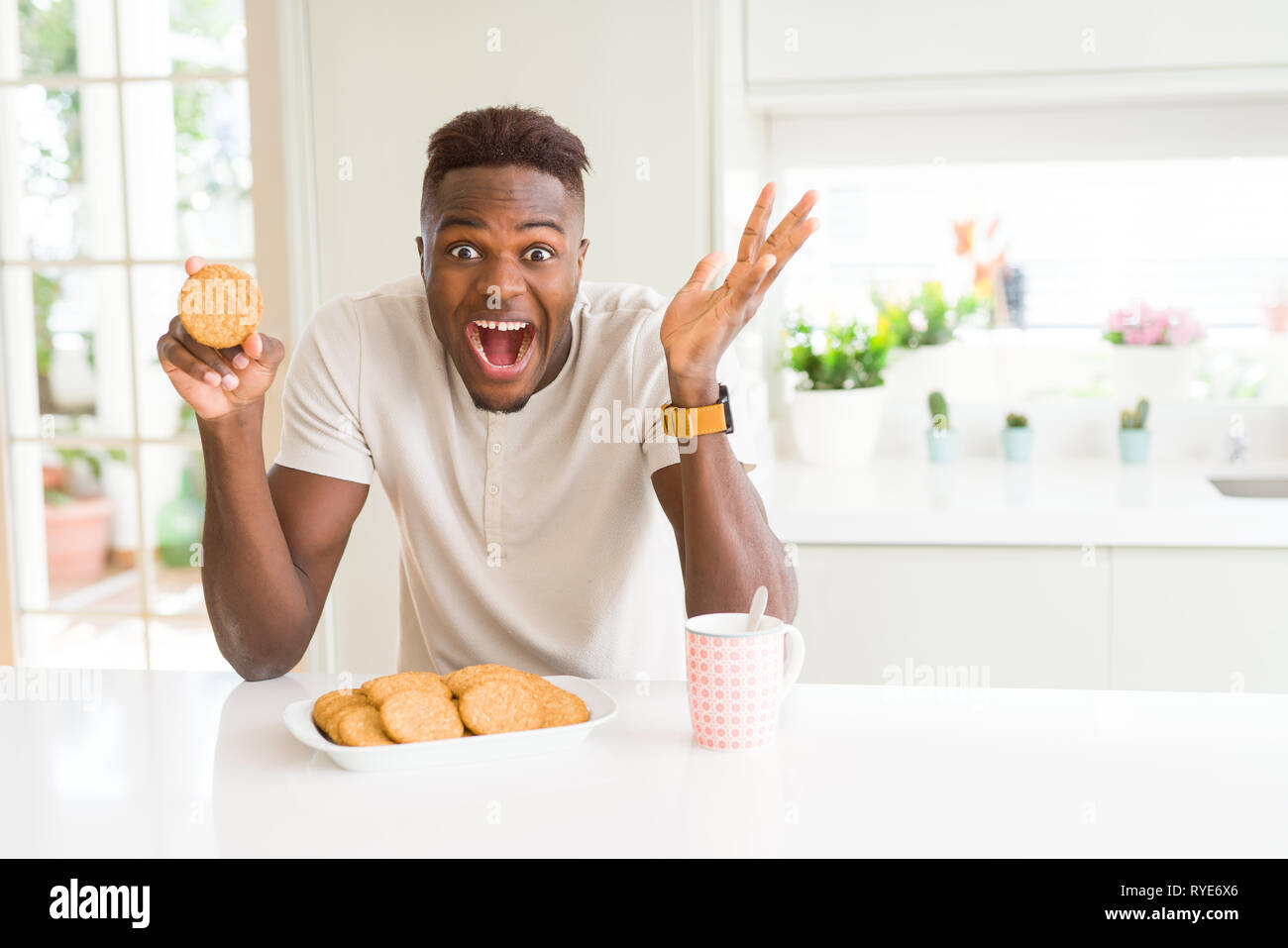 African american man eating healthy whole grain biscuit very happy and ...