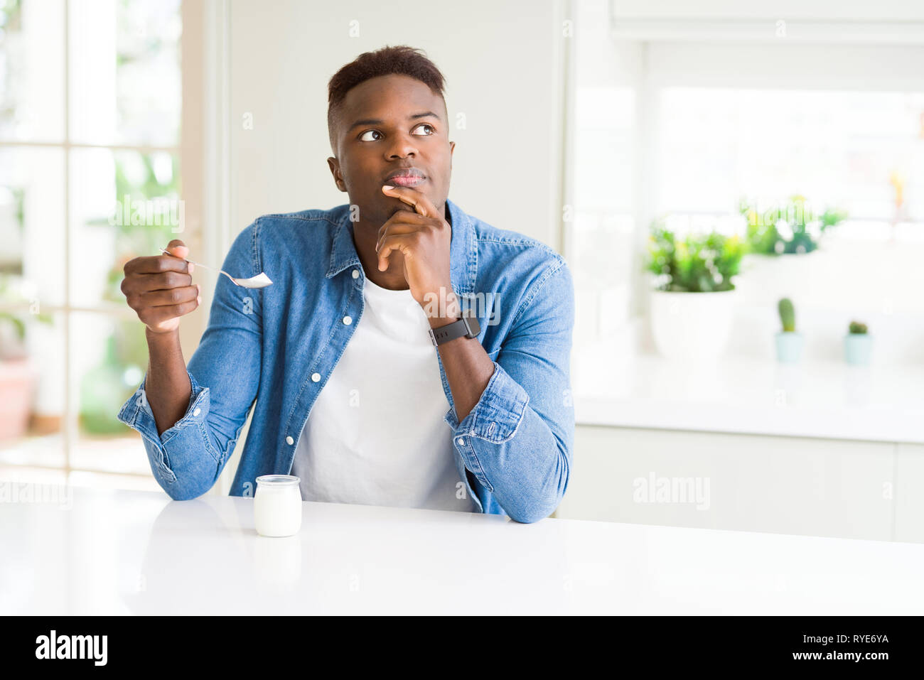 African american man eating healthy natural yogurt with a spoon serious ...