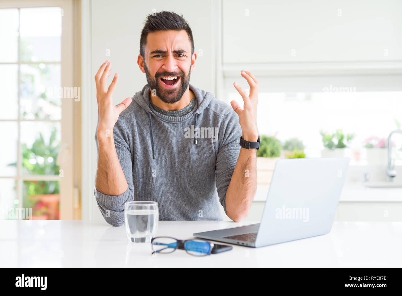 Handsome hispanic man working using computer laptop crazy and mad ...